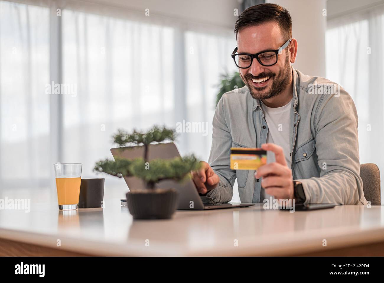 Smiling adult man, entering his bank account password in his laptop ...