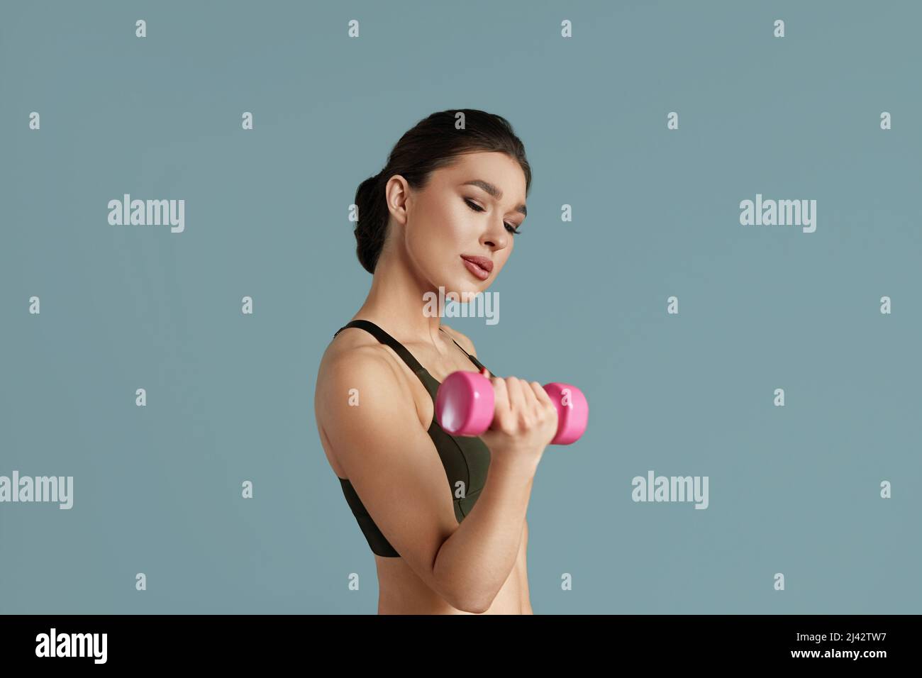 Woman doing exercises with dumbbells, strengthening her body at home ...