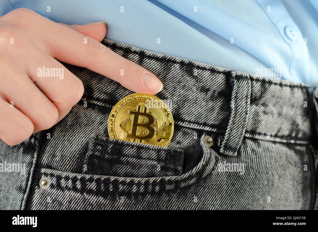 A woman's hand puts a golden bitcoin in a jeans pocket, close-up Stock ...