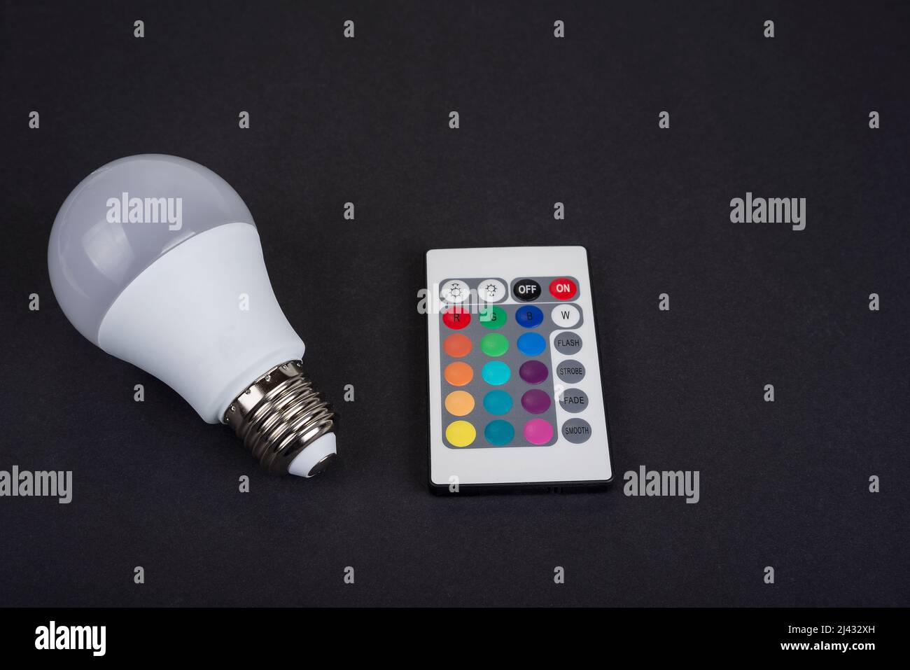 Multi color led bulb with a remote control on a black background Stock ...