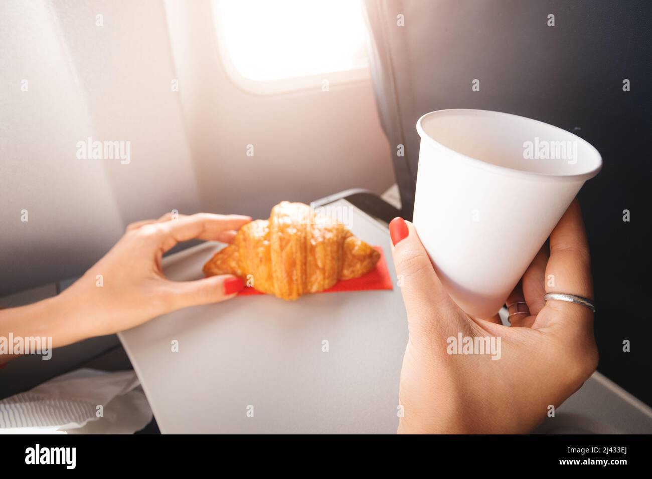 A girl passenger eats a croissant and drinks coffee sitting by the ...