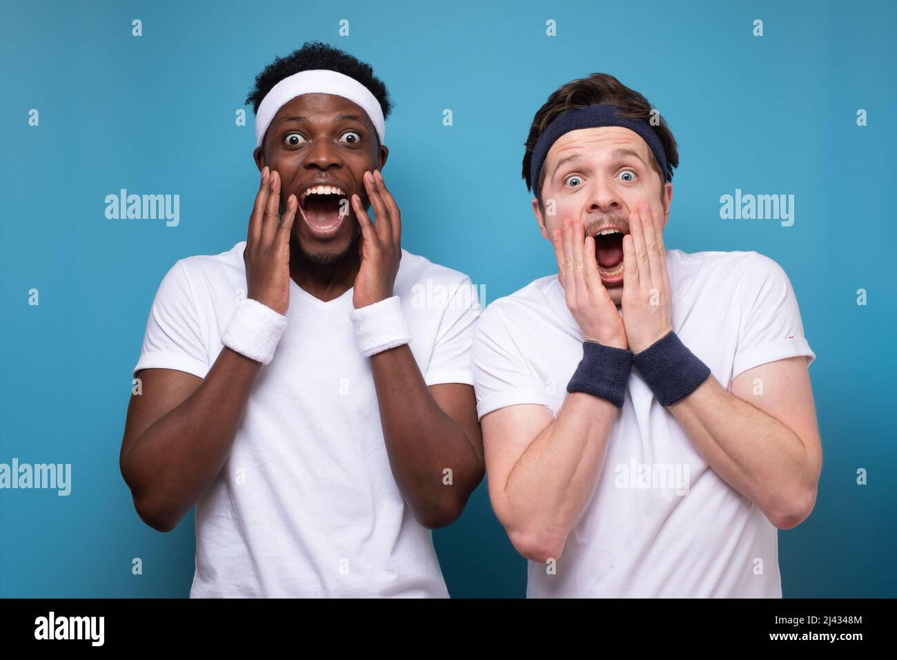 Two young men are ecscatic raising hands to their face. Positive sport ...