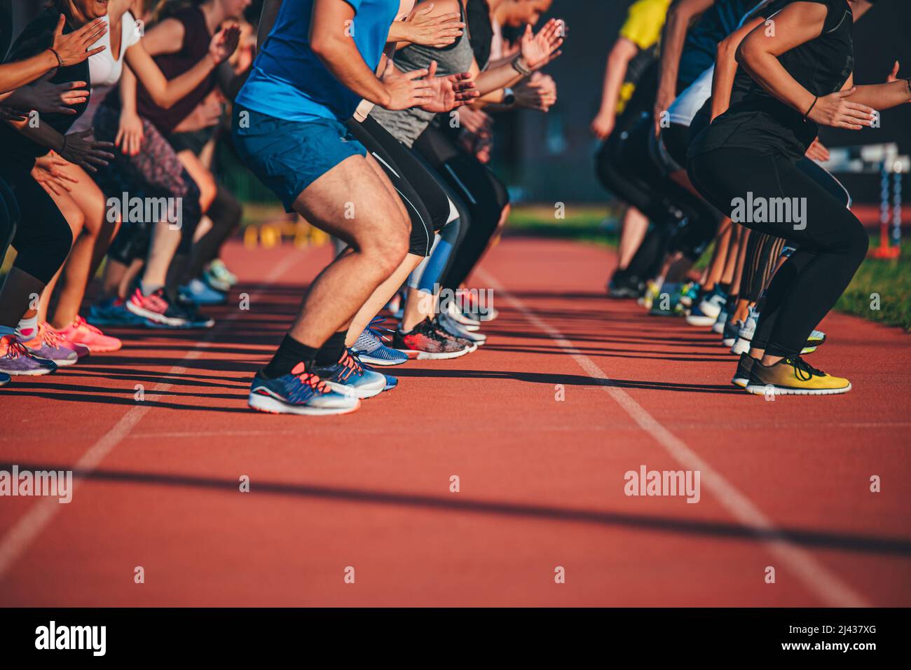 Team training outdoors on an athletic track. Group warm-up before the ...