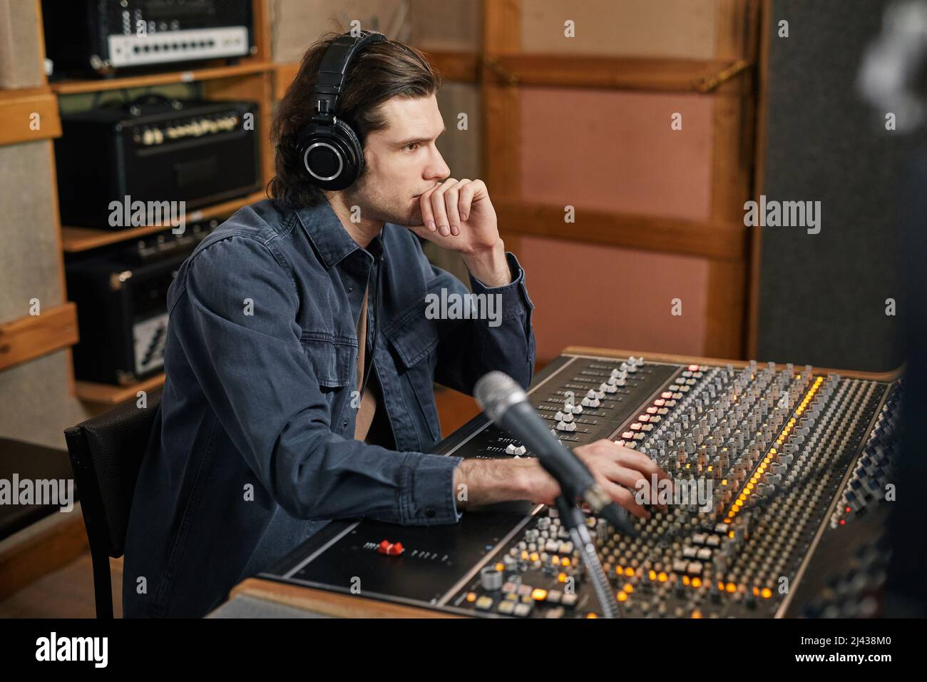 Side view portrait of focused young man wearing headphones at audio ...