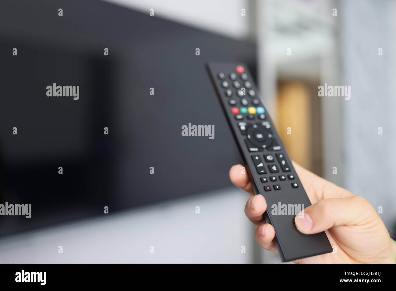 Black remote control in hand in front of TV Stock Photo - Alamy