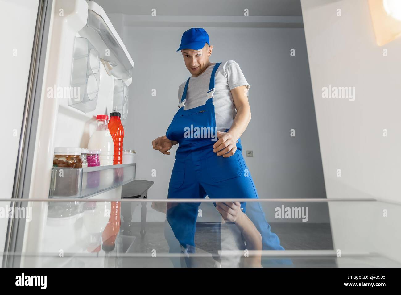 Cheerful male repairman in uniform is dancing a private dance near the ...