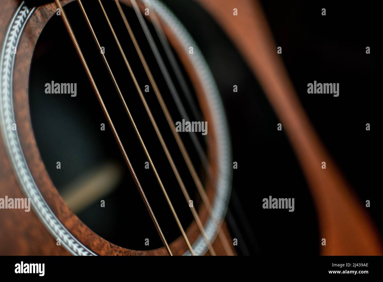 An angled close-up view of the sound hole and steel strings of an ...