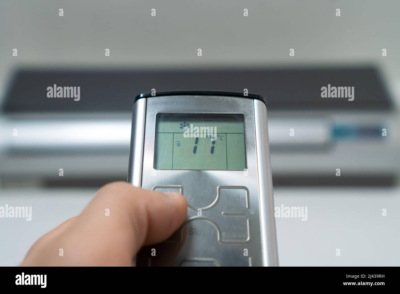 Close-up of a man's hand with a gray remote control pointing at the air ...