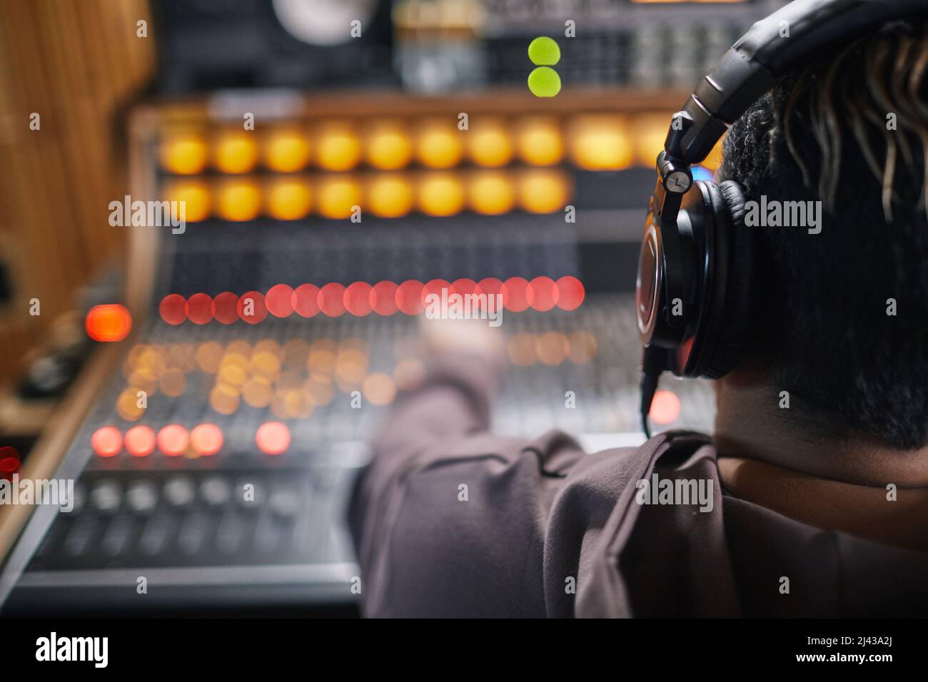 Back view at young musician wearing headphones at audio workstation in ...