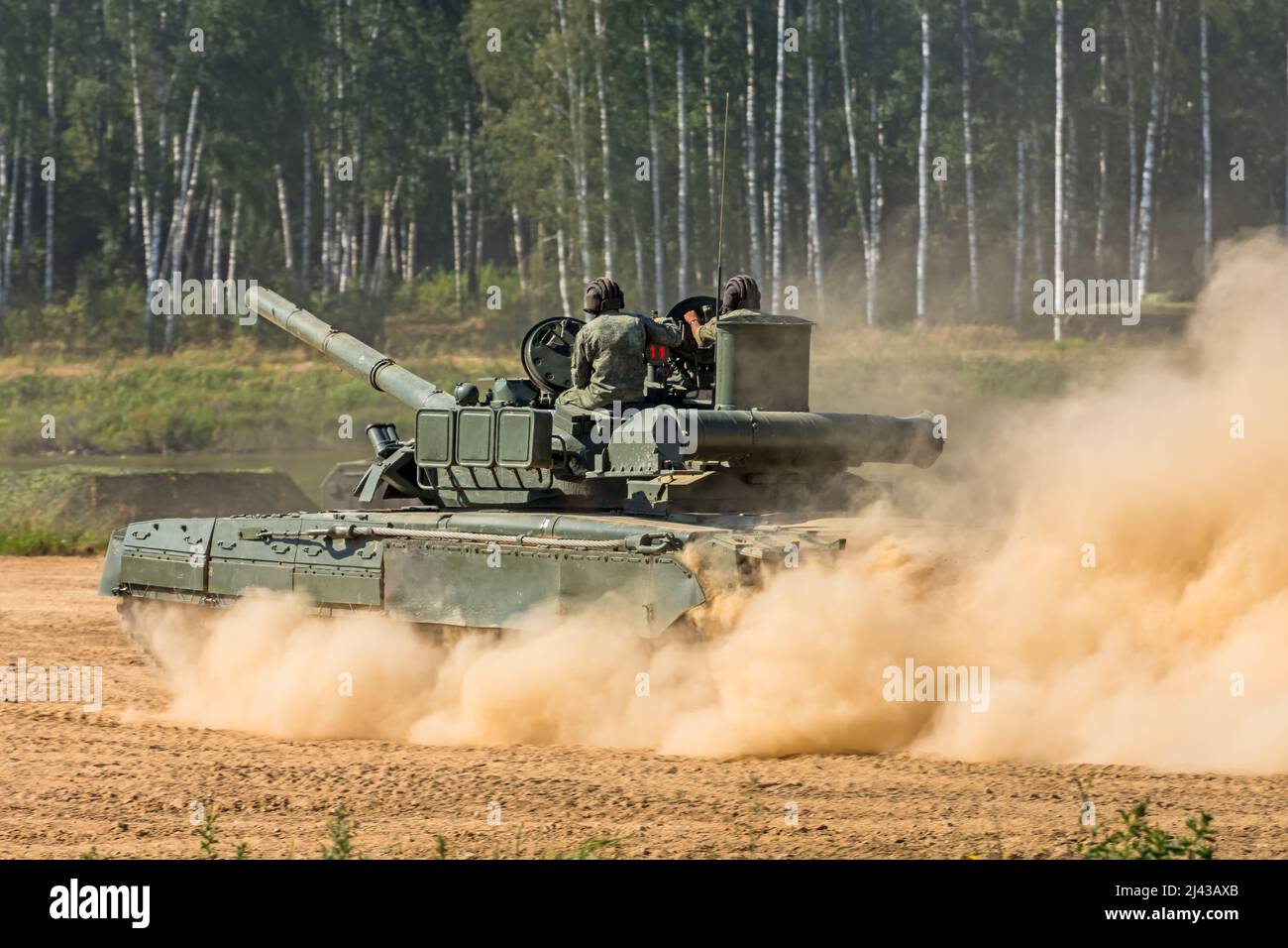 Heavy armor tank with dust from under the caterpillars in the field of ...