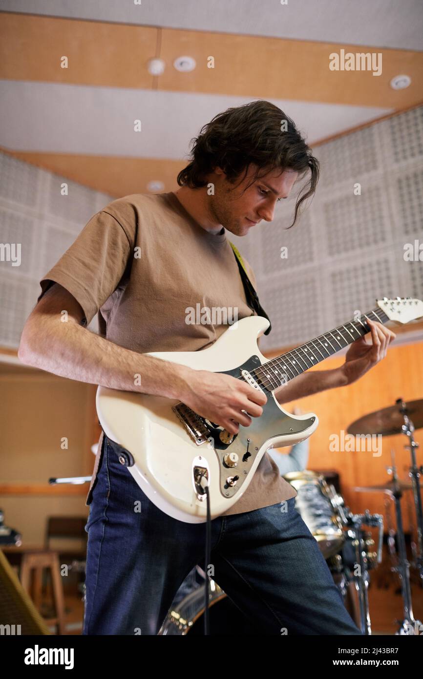 Low angle portrait of young guitarist playing music in professional ...