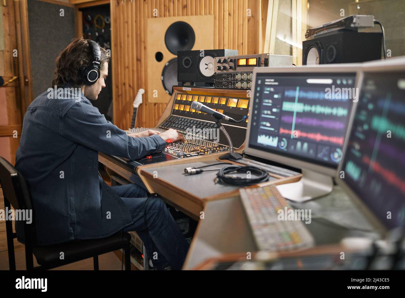 Wide angle at music producer operating audio workstation in ...