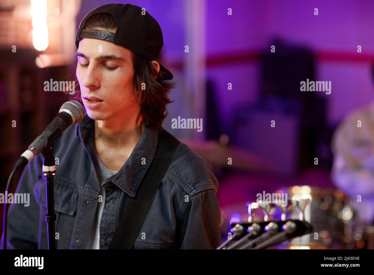 Portrait of talented young musician singing to microphone with eyes ...