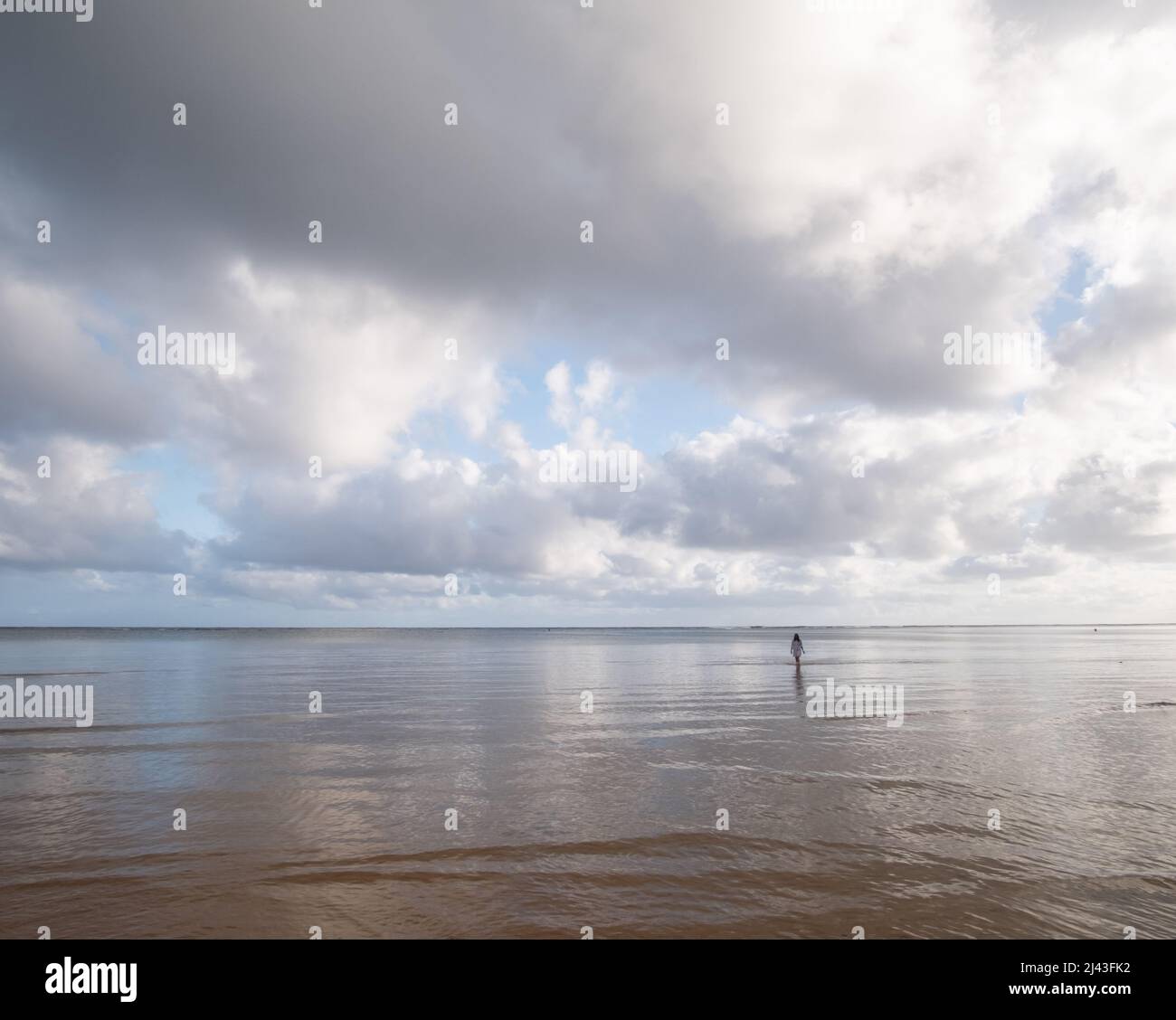 wide angle of woman walking along tide flow Stock Photo - Alamy