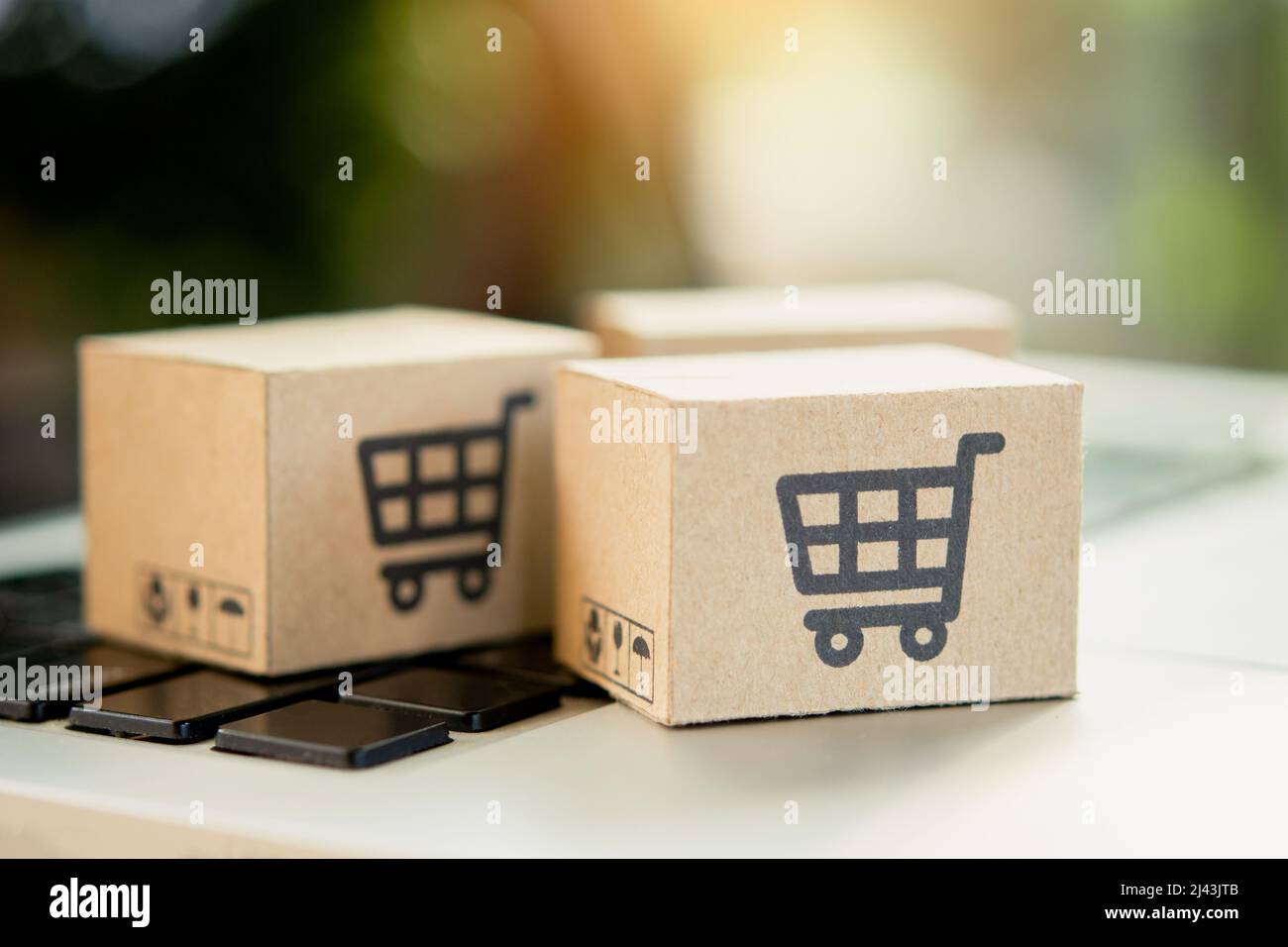 Shopping online. Cardboard box with a shopping cart logo on laptop ...