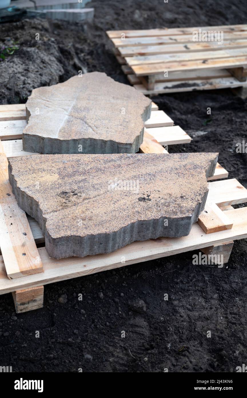 Work on laying irregularly shaped concrete tiles in the garden during ...