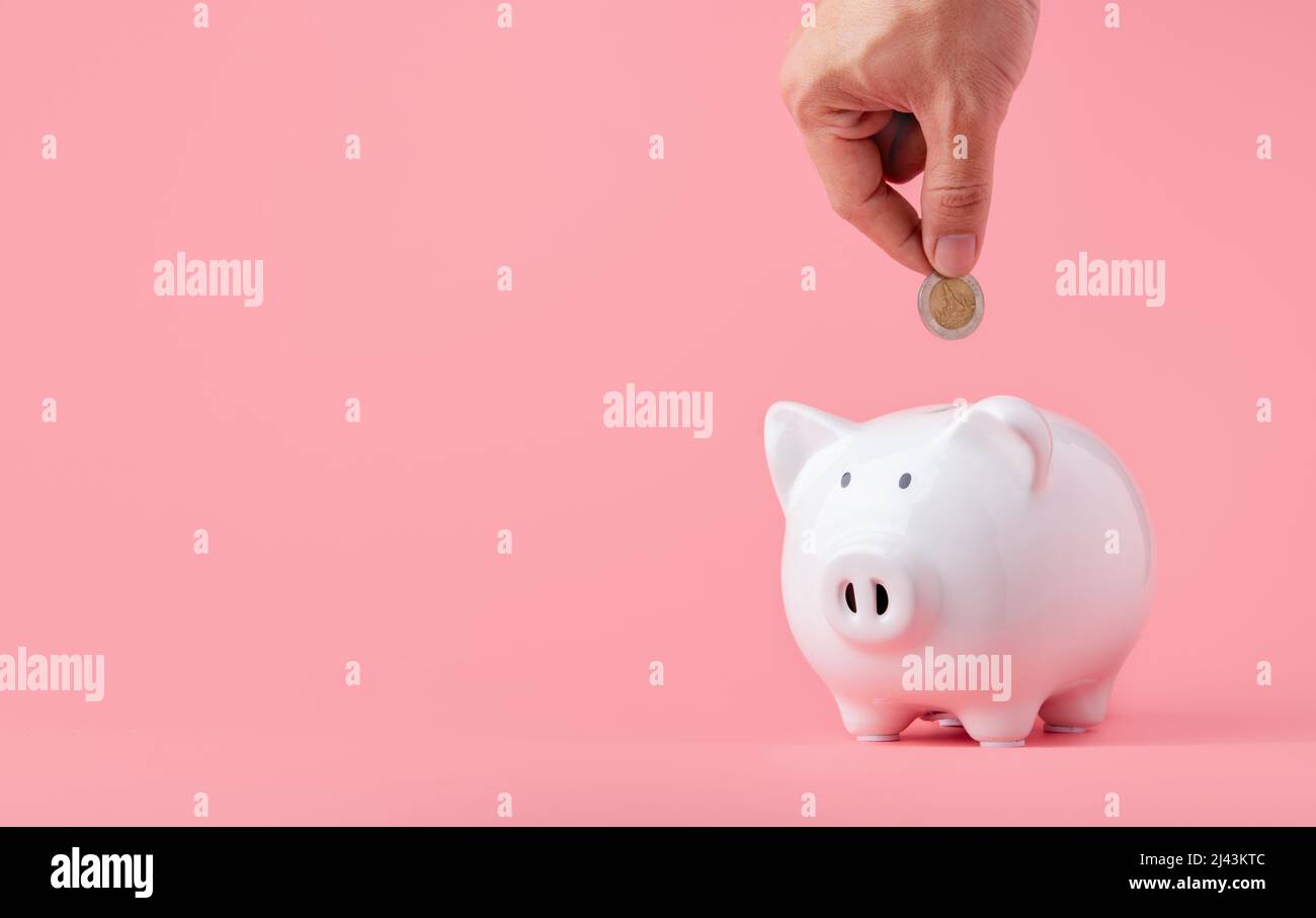 Money saving and investment concept. Hand putting coin to piggy bank on ...