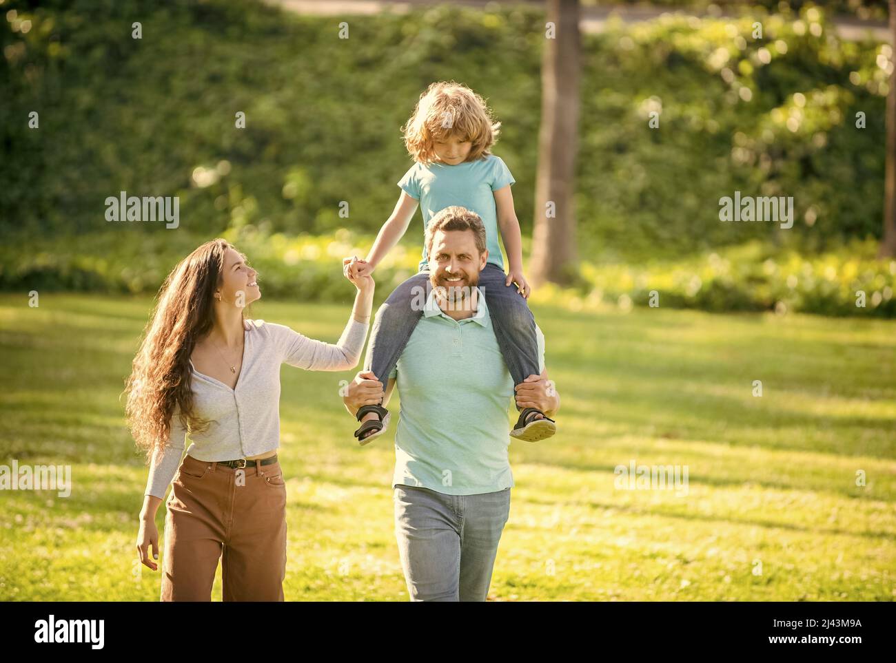 Happy family of mother and father carrying boy child on shoulders ...