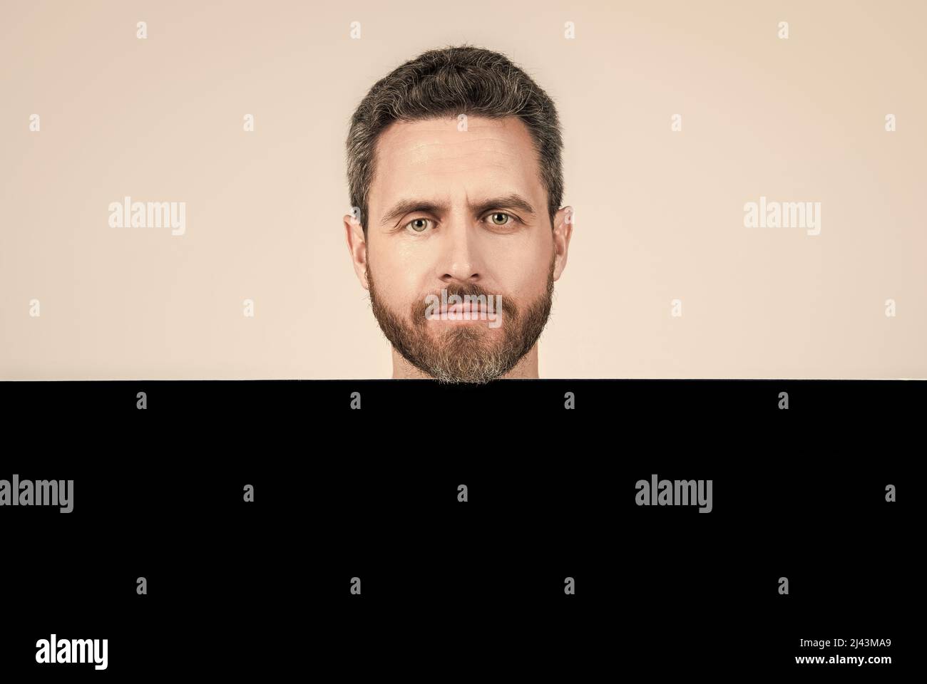mature bearded man behind blank black paper banner with copy space for ...
