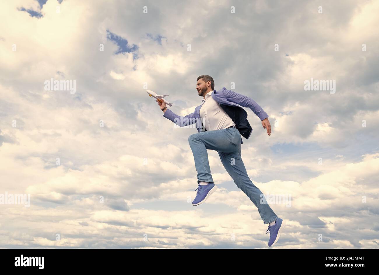 happy man businessperson in jacket hold toy plane on sky background run ...