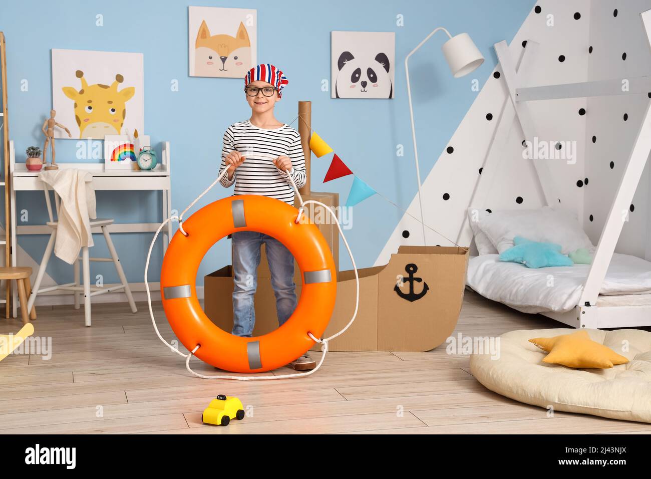 Funny little boy playing with cardboard ship and lifebuoy at home Stock ...