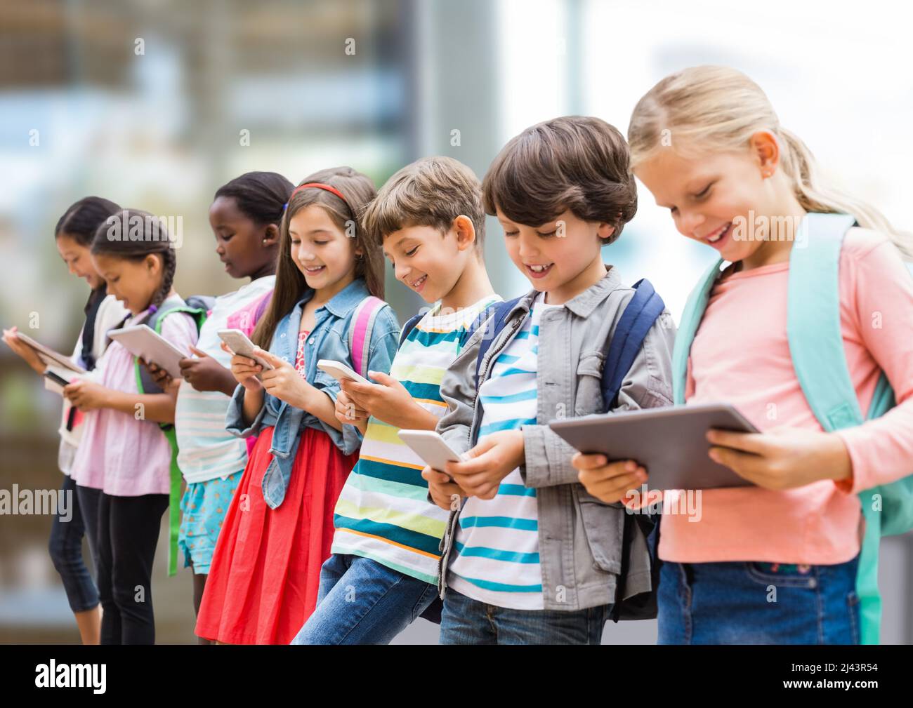 Group of diverse school students using electronic devices against ...