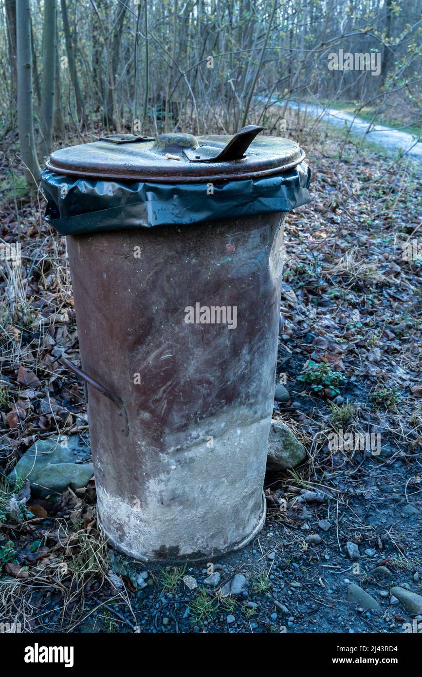 Old, deformed, rusty metal trash can in remote rural area. Thick ...