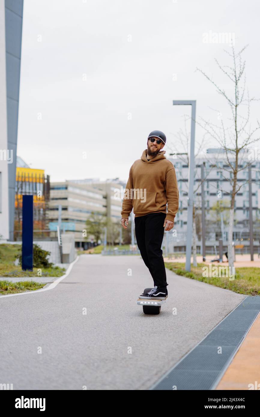Young man in a helmet rides an electric skateboard. Onewheel rider in ...