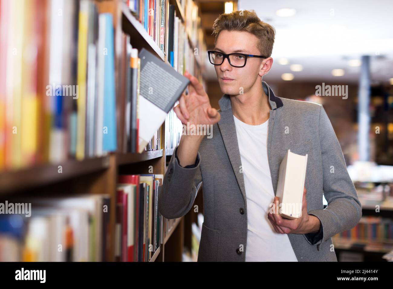 Intelligent student choosing books on shelves Stock Photo - Alamy