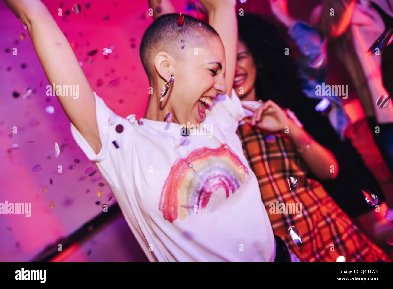 Woman dancing with her friends at a house party. Cheerful young women ...