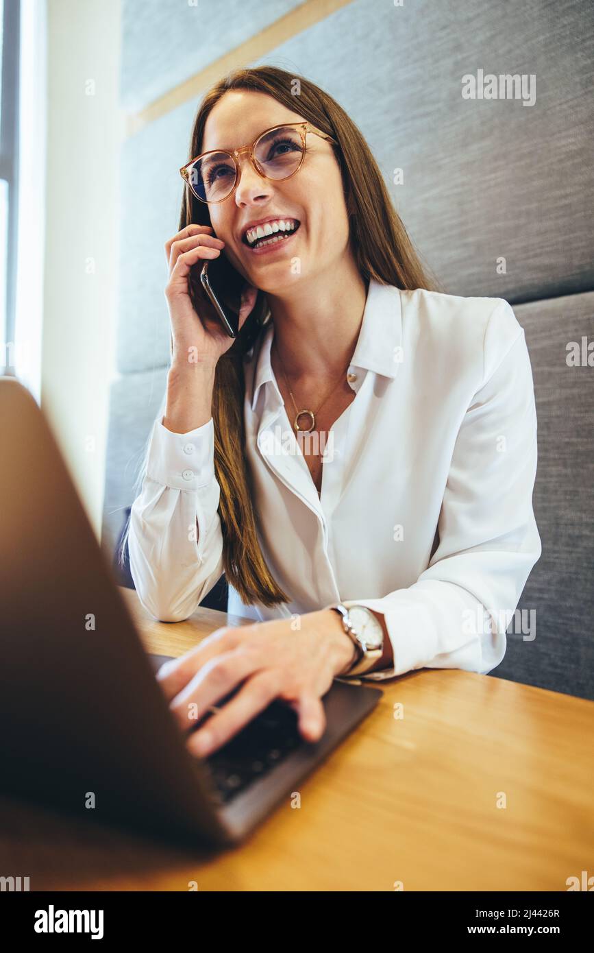 Smiling businesswoman taking a phone call. Cheerful young businesswoman ...