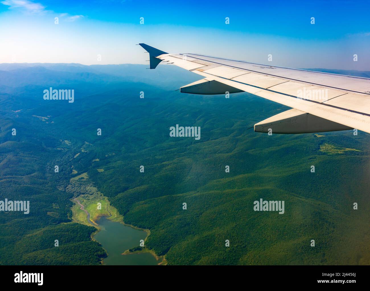 View of airplane wing, blue skies and green land during landing ...
