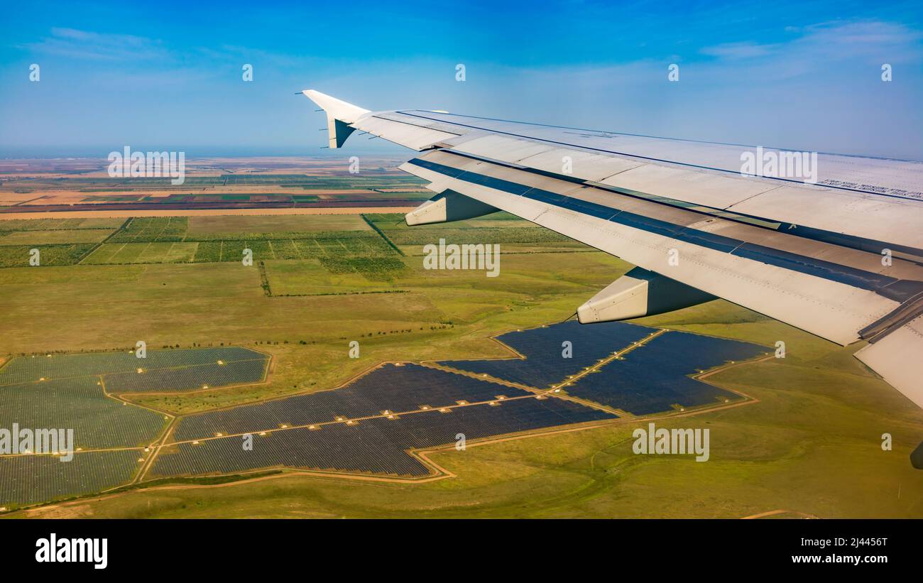 View of airplane wing, blue skies and green land during landing ...