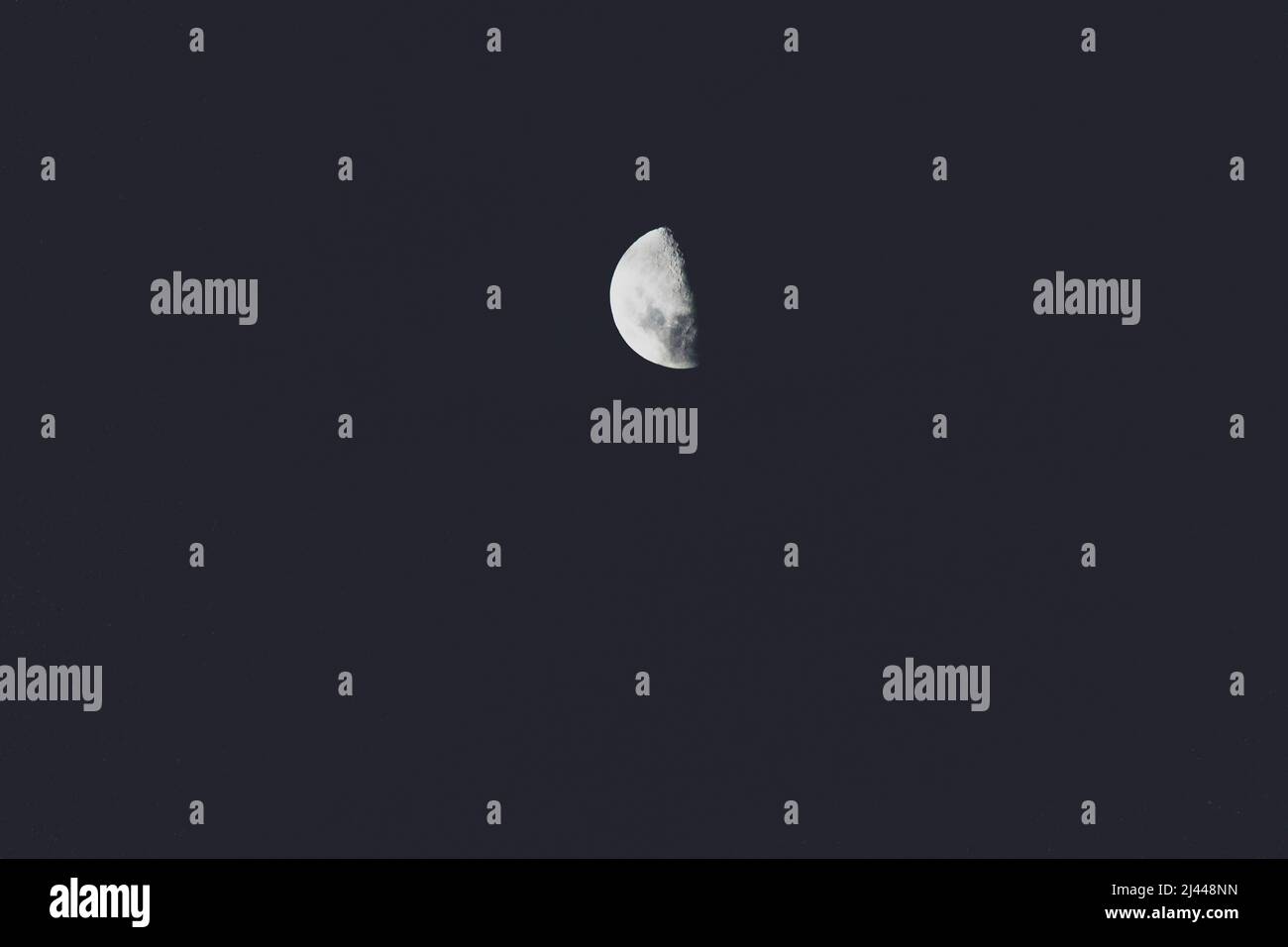 half moon in the night sky shot with telephoto lens with faded black ...
