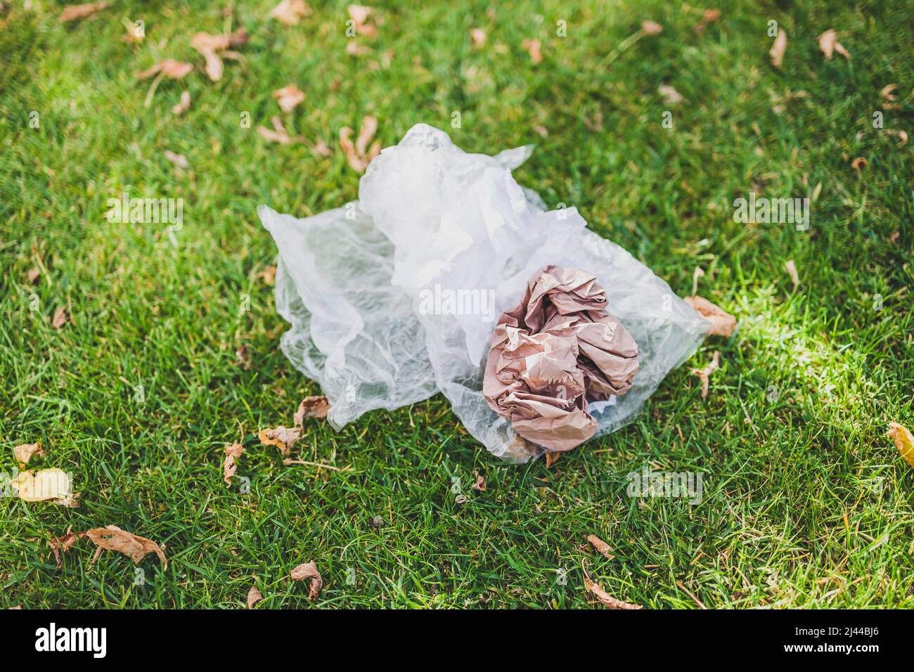 plastic bags and litter abandoned on green lawn, concept of respecting ...