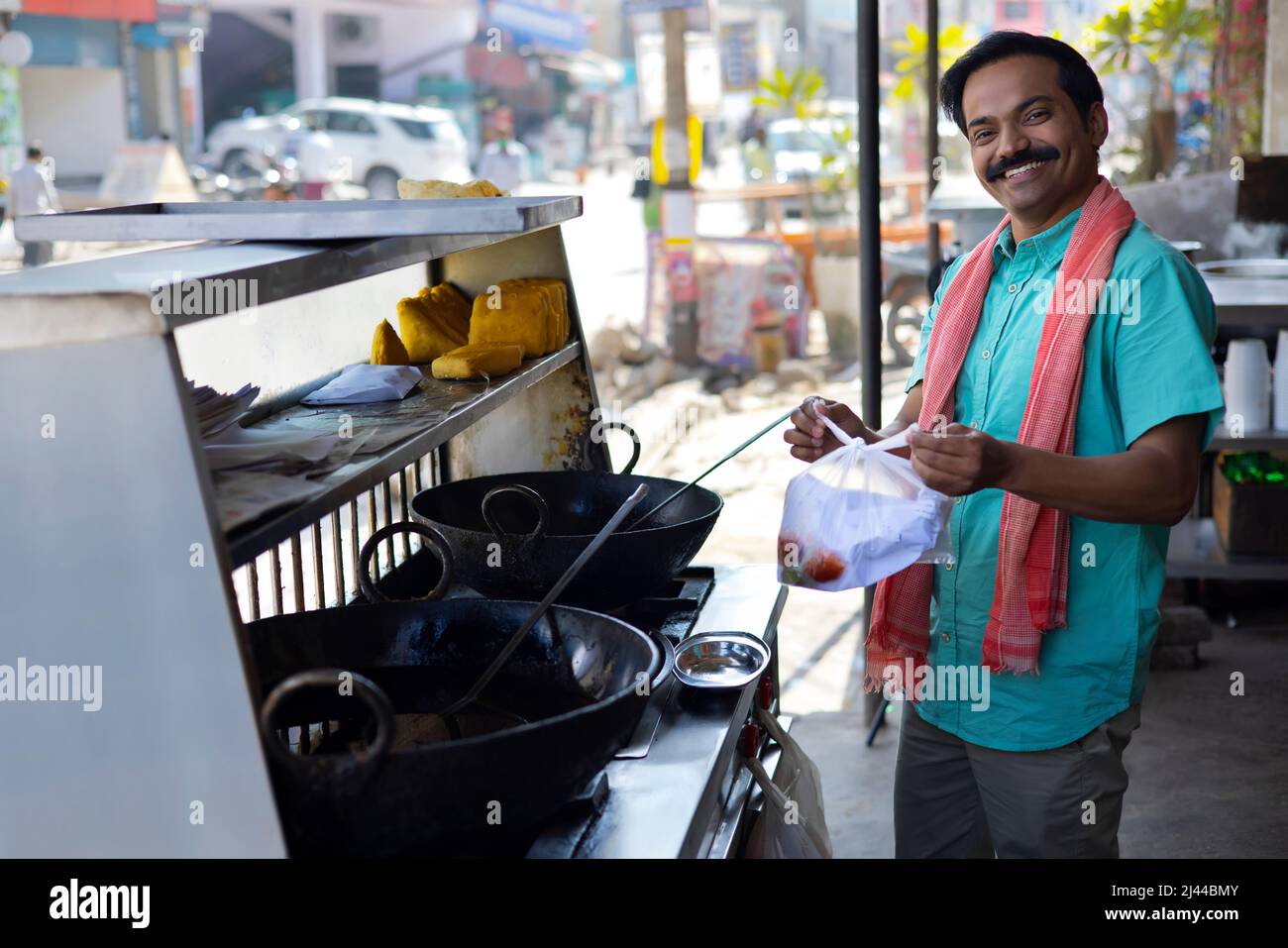 Happy street food vendor packing food into package Stock Photo - Alamy