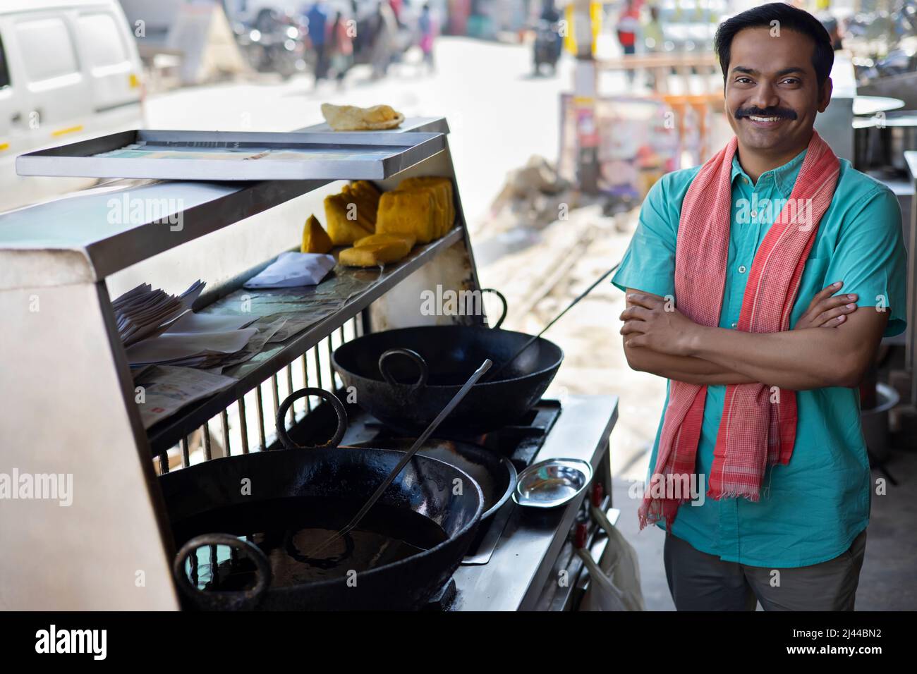 Happy street food vendor posing in front of camera with arms folded ...