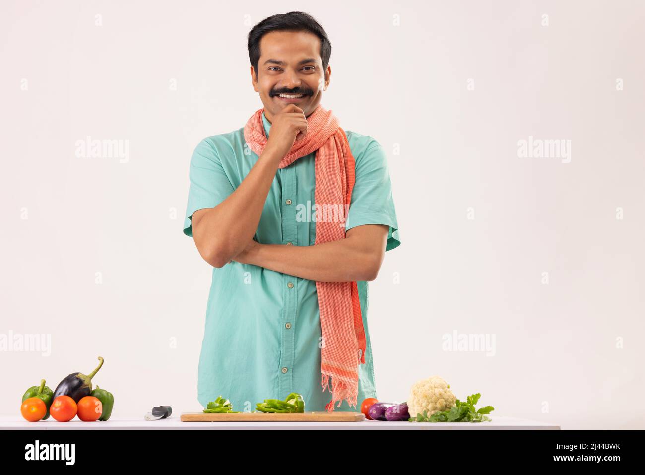 Cook servant posing in front of camera with a hand on chin in kitchen ...