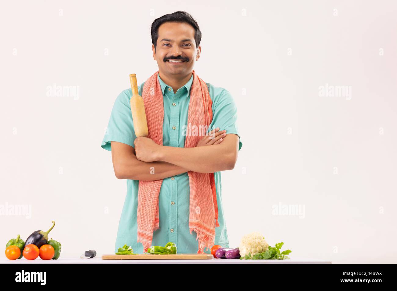 Cook servant posing in front of camera with roller pin and arms folded ...