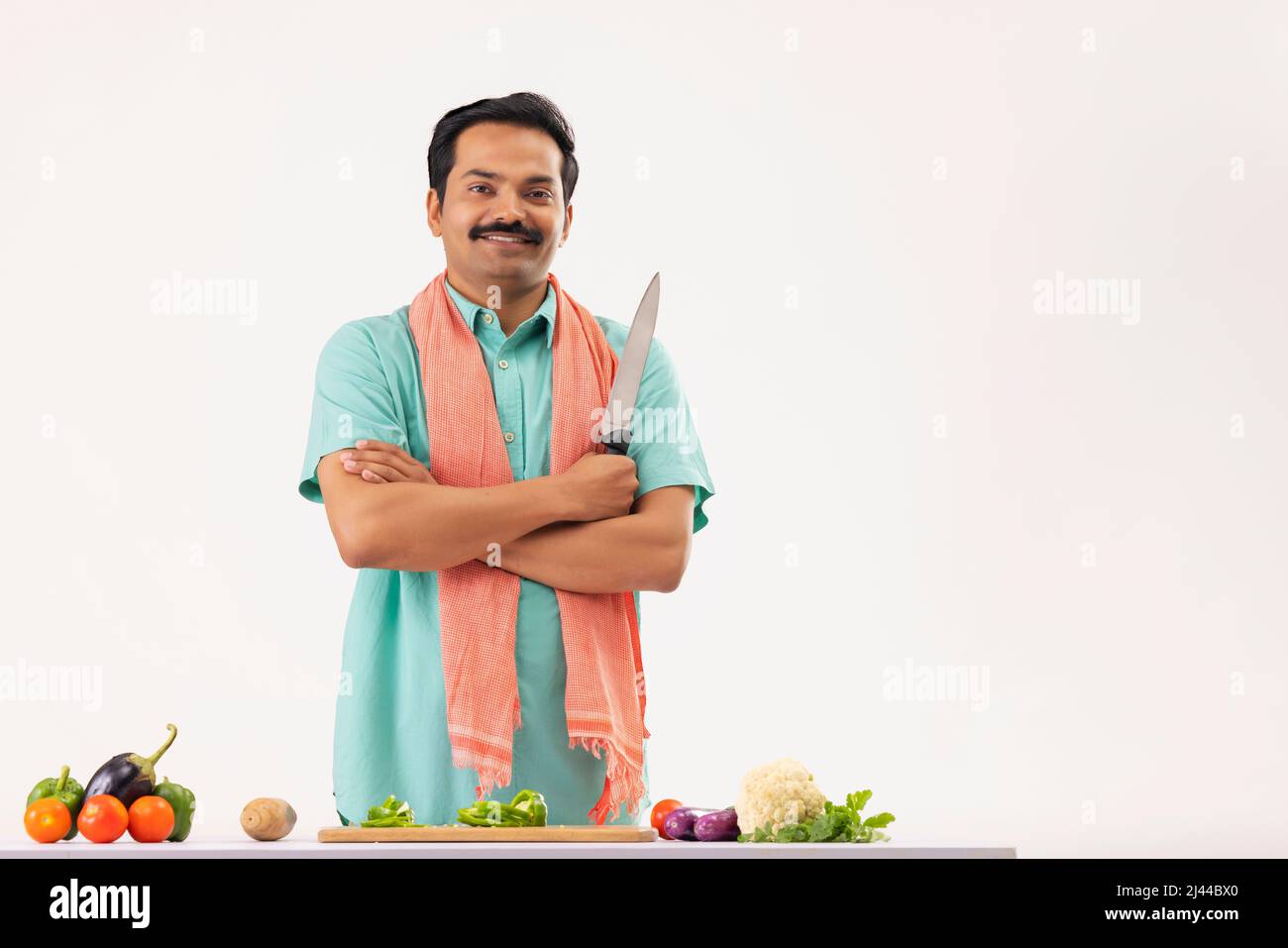 Cook servant posing in front of camera with knife and arms folded in ...