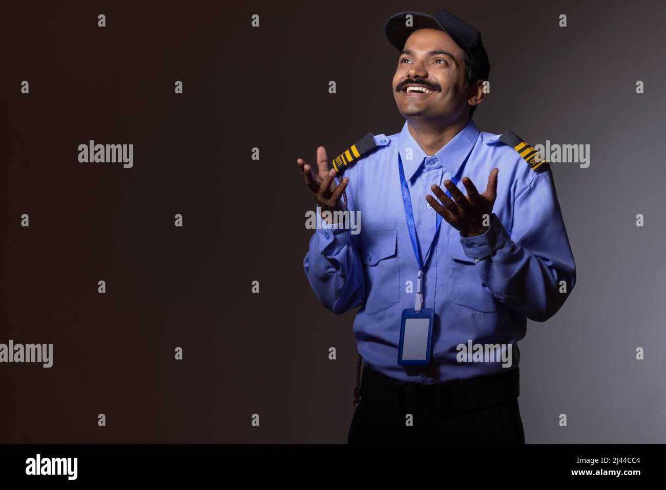Indian Security guard wearing a security uniform over isolated dark ...