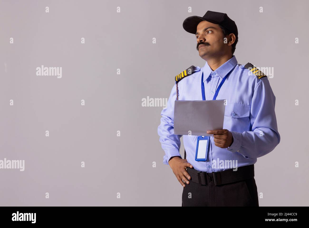 Security guard looking away with holding papers in hand Stock Photo - Alamy