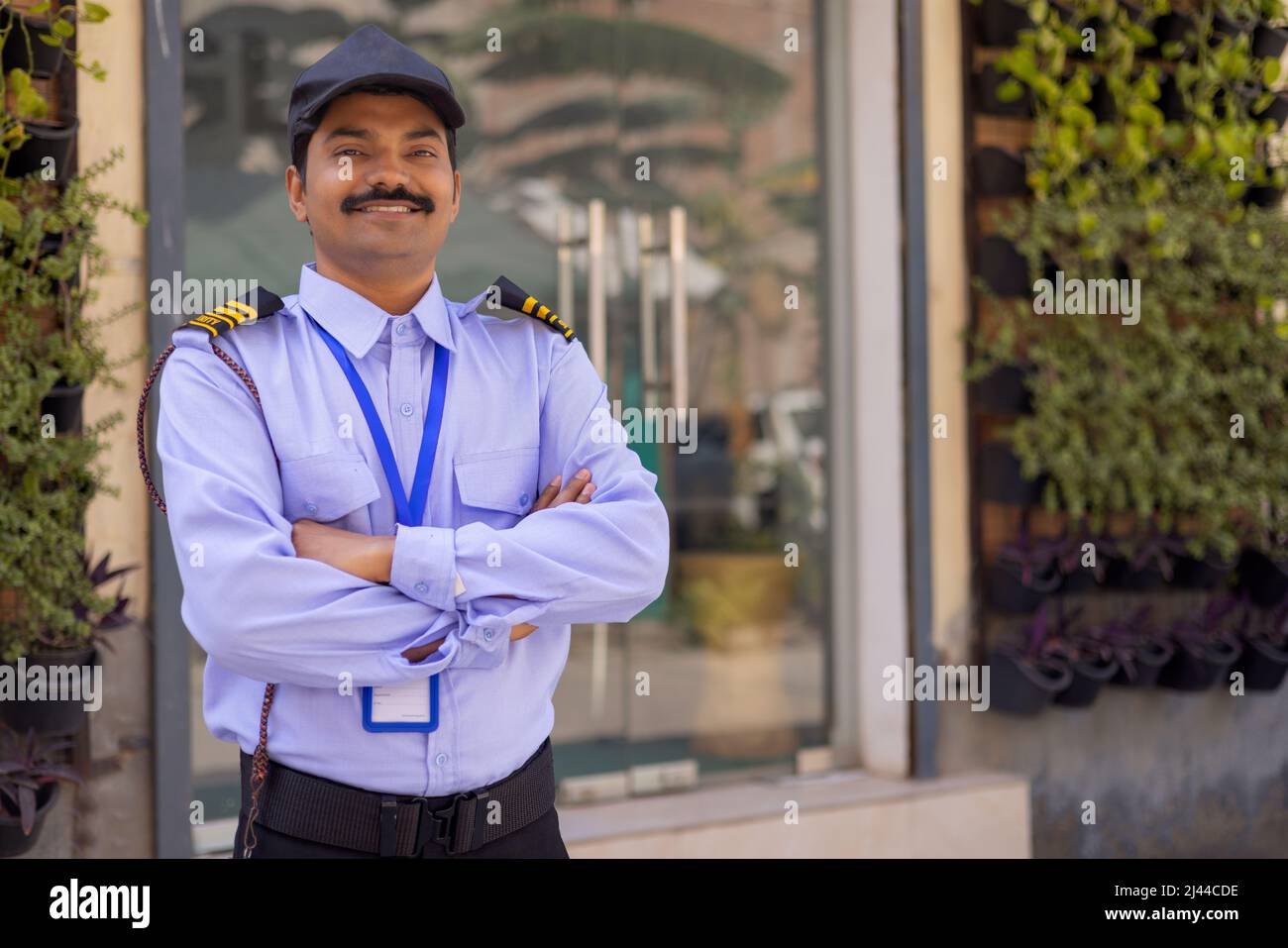 Portrait of security guard with arms folded while working at gate Stock ...