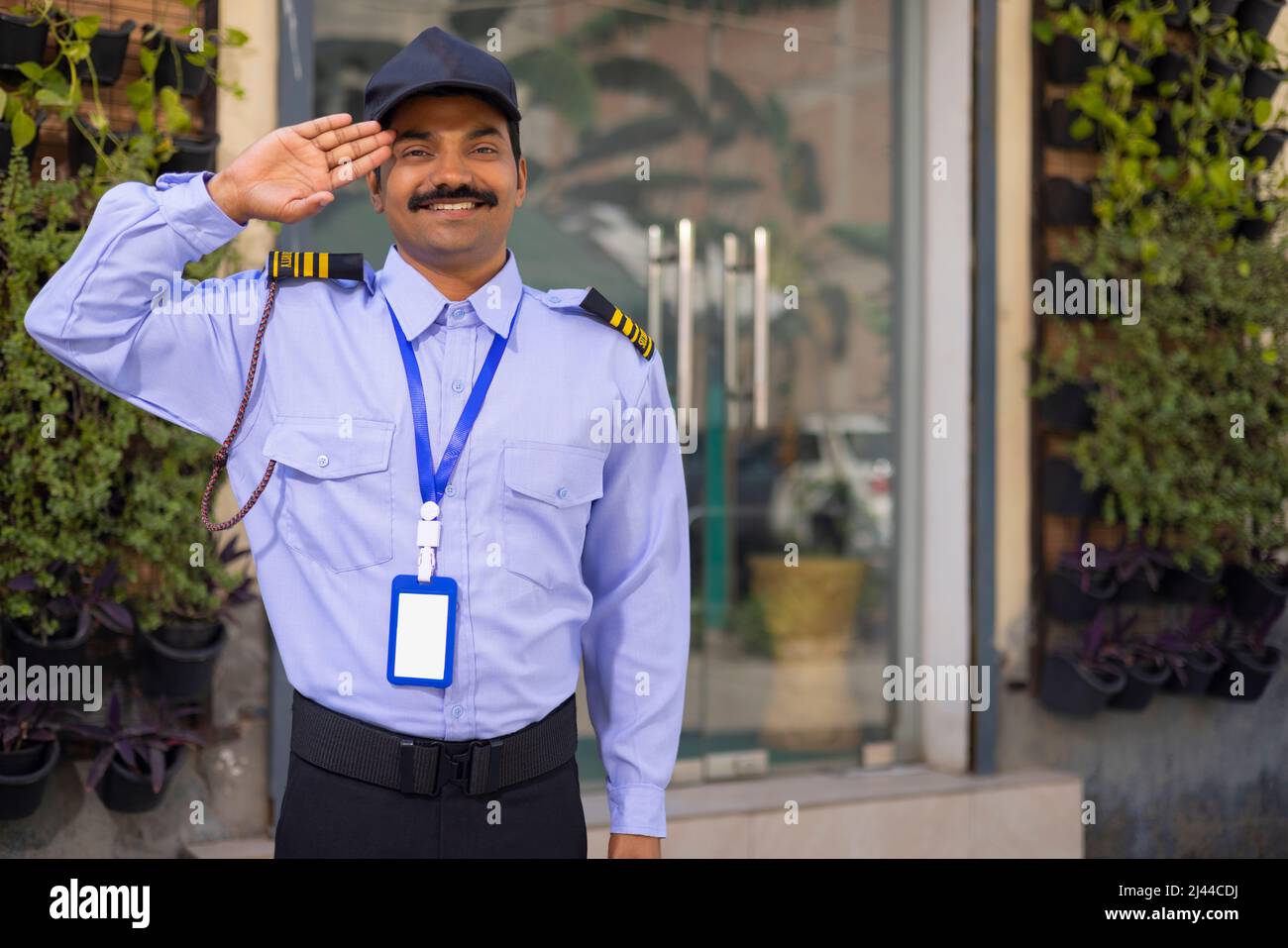 Portrait of security guard saluting while working at gate Stock Photo ...