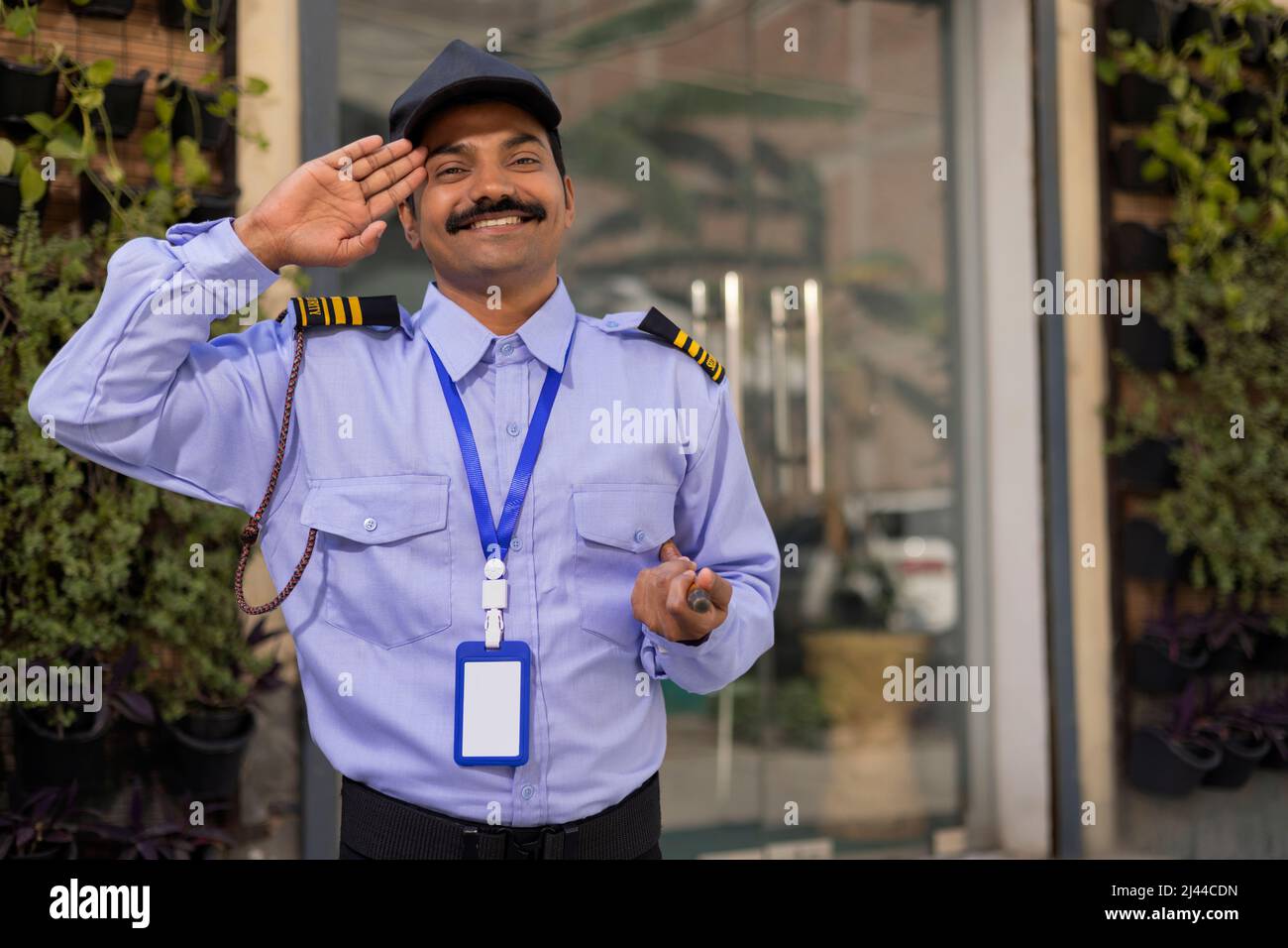 Portrait of security guard saluting while working at gate Stock Photo ...