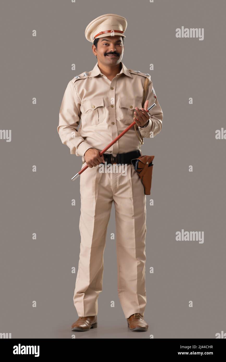 Portrait of an Indian policeman standing with baton in hand Stock Photo ...