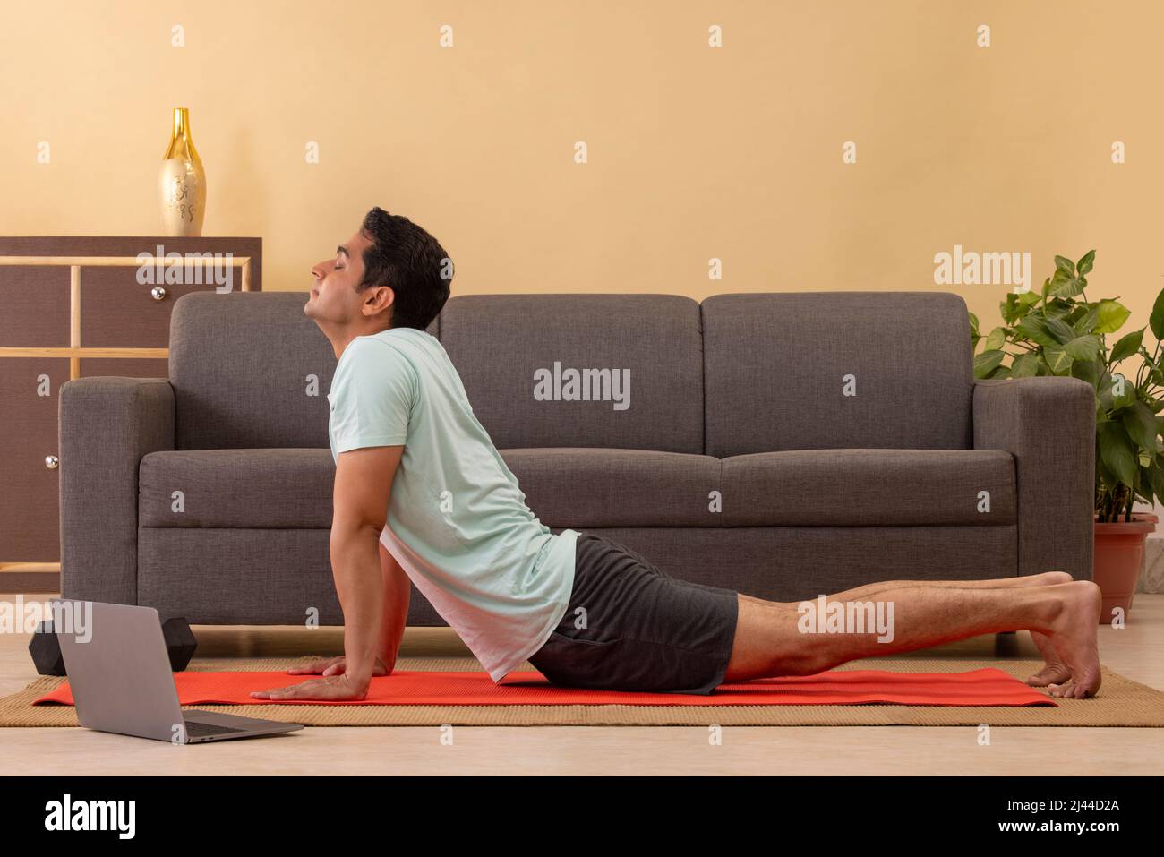 Male Indian Yoga instructor conducting an online class with laptop ...