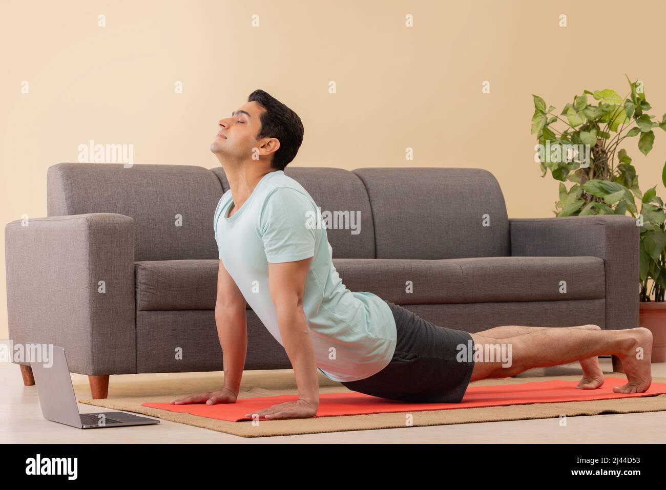 Male Indian Yoga instructor conducting an online class with laptop ...