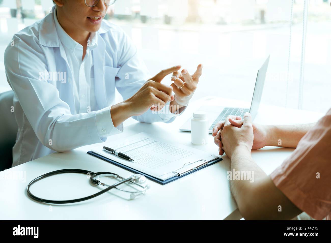 Male patient listening to doctor at desk and consulting with healthcare ...