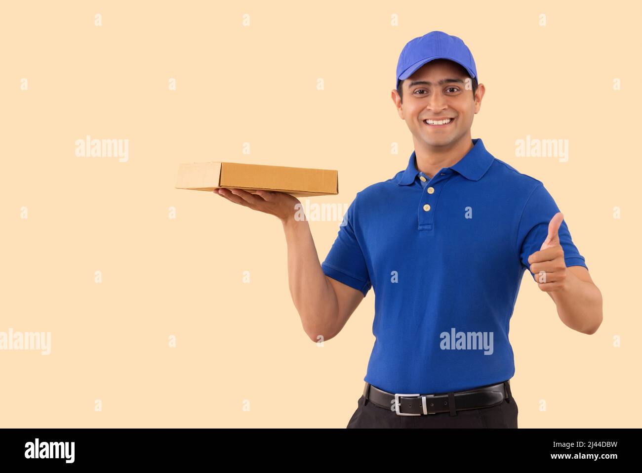 Portrait of a courier delivery boy holding parcel on palm and gesturing ...